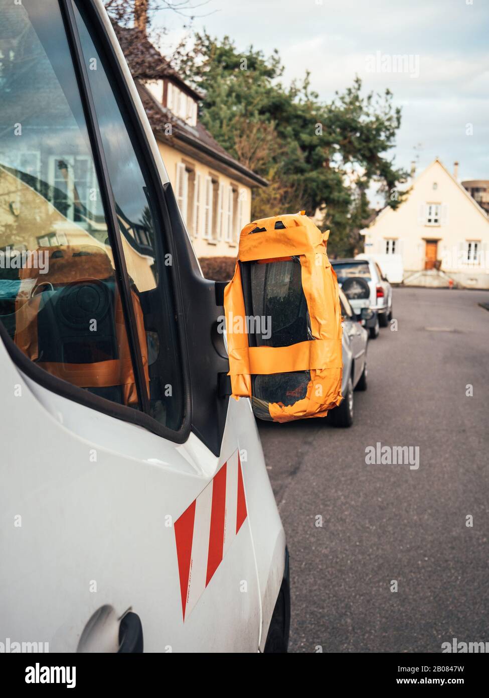 Construction van with broken rear view mirror glued with orange worker ...