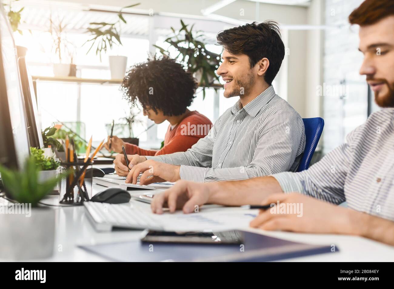 Colleagues working in front of computers in coworking space Stock Photo ...