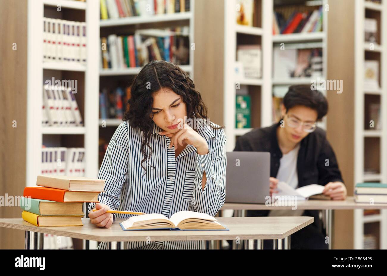 Brazilian girl doing research sitting at desk in library Stock Photo ...