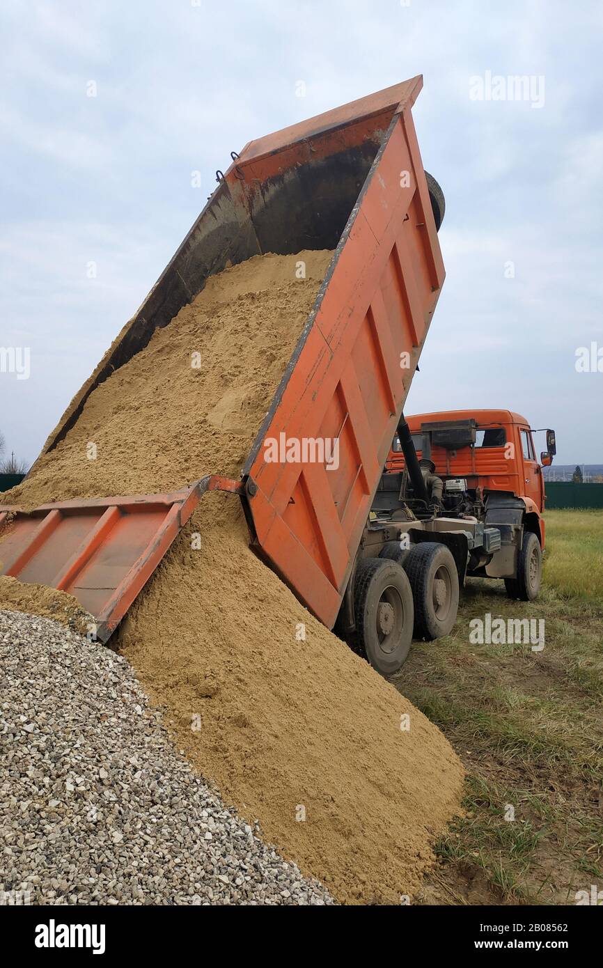 A dump truck unloads sand at a construction site Stock Photo - Alamy