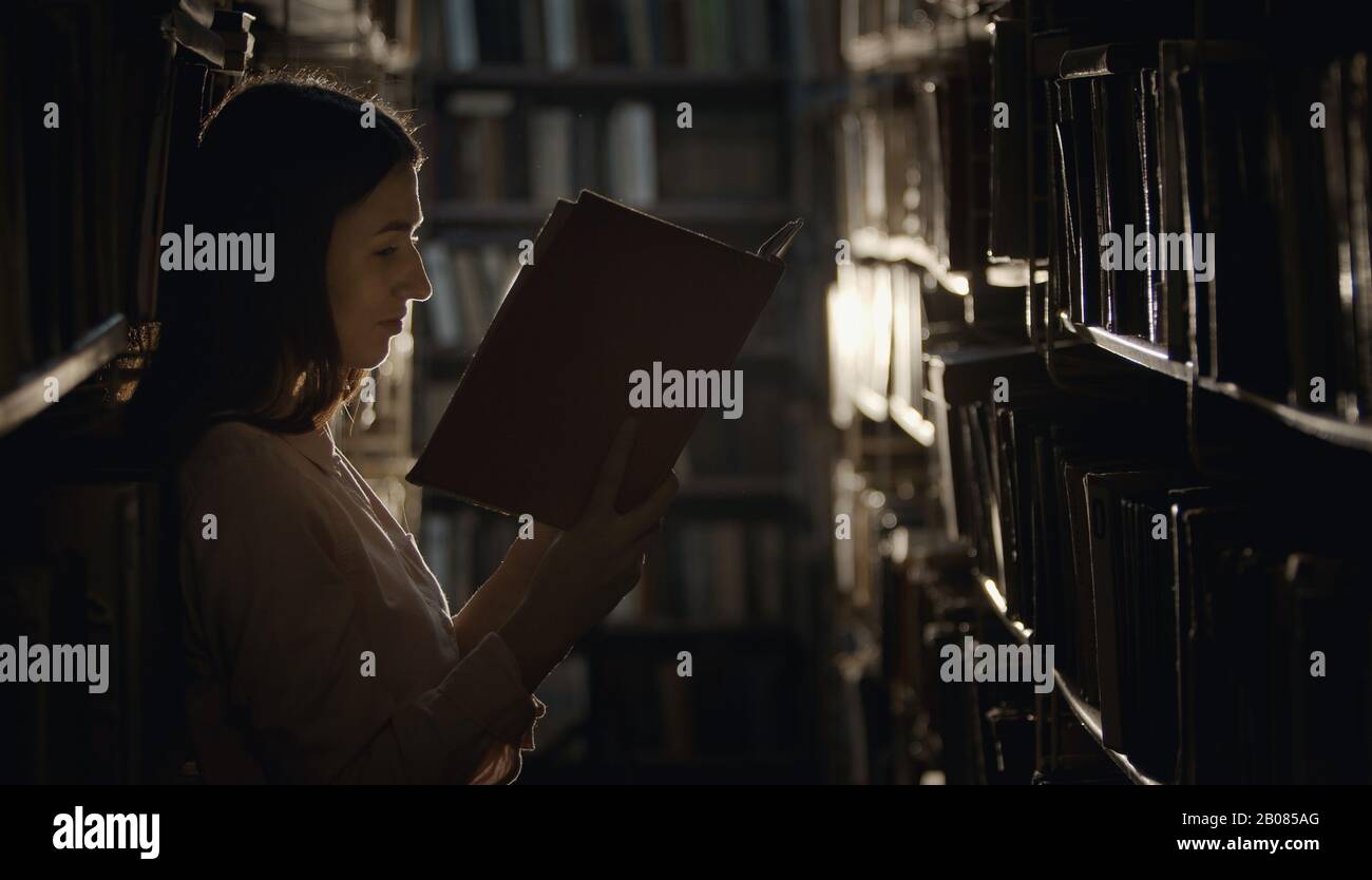 Woman reading book, dark library Stock Photo - Alamy
