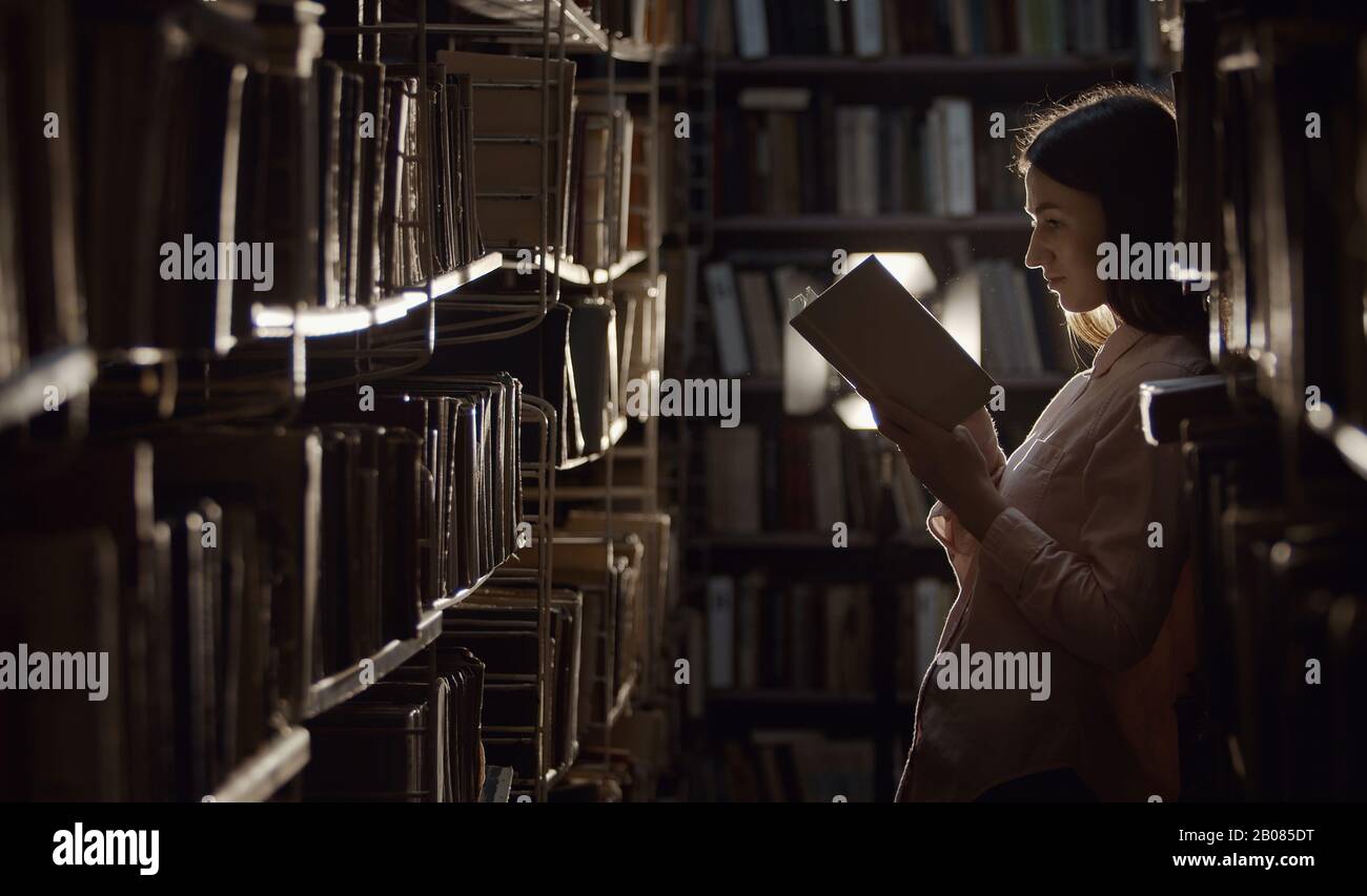 Lady reading book, dark library Stock Photo - Alamy