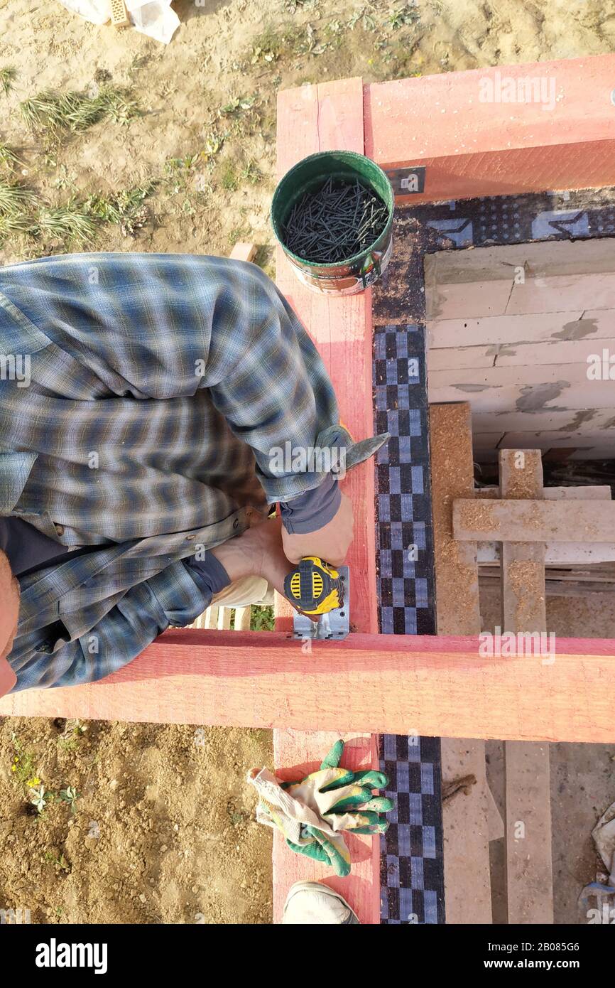 In the roof rafters the worker screws the screws into the screwdriver ...