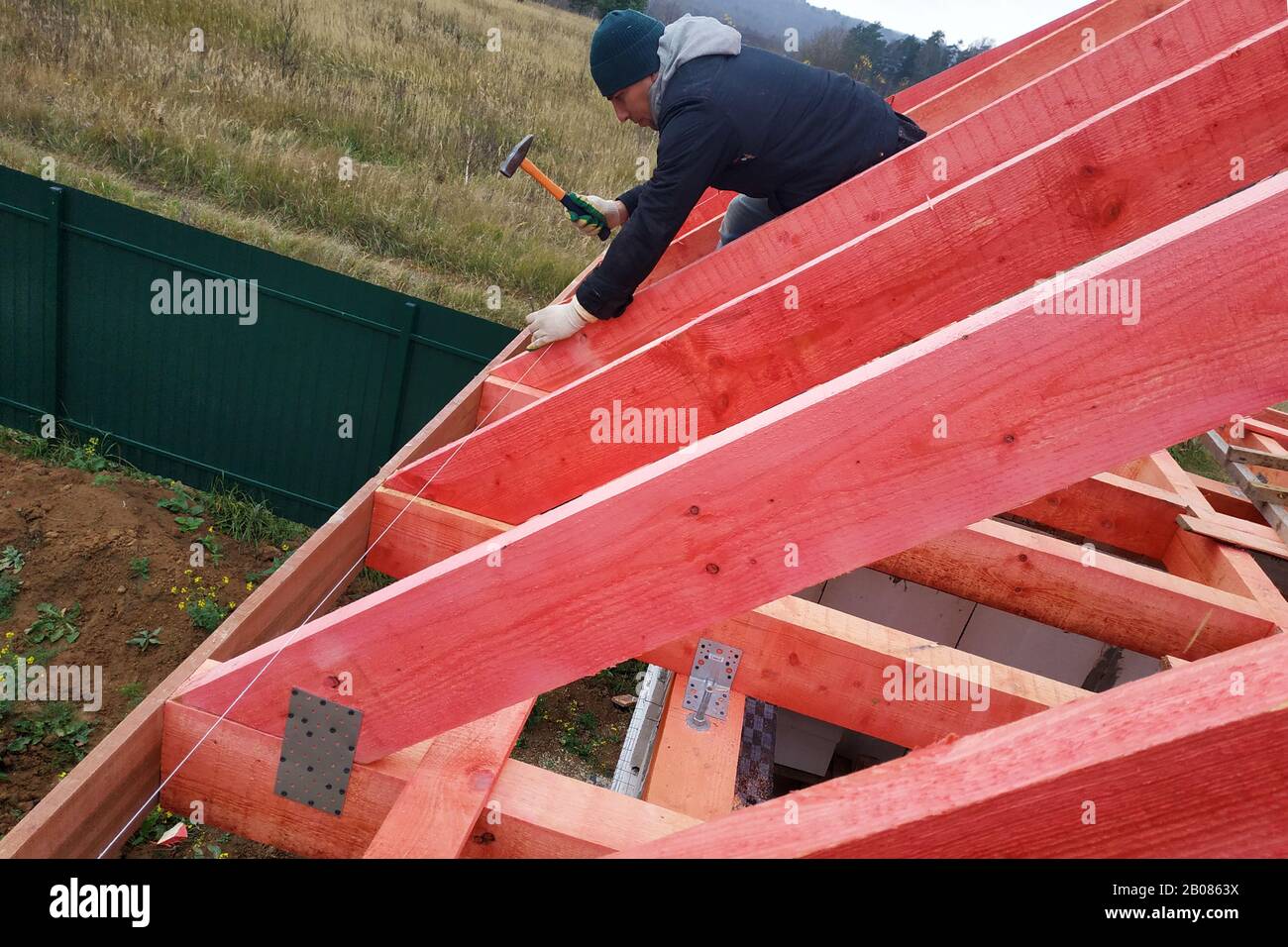 A man fastens two wooden beams with a self-tapping screw, installing ...
