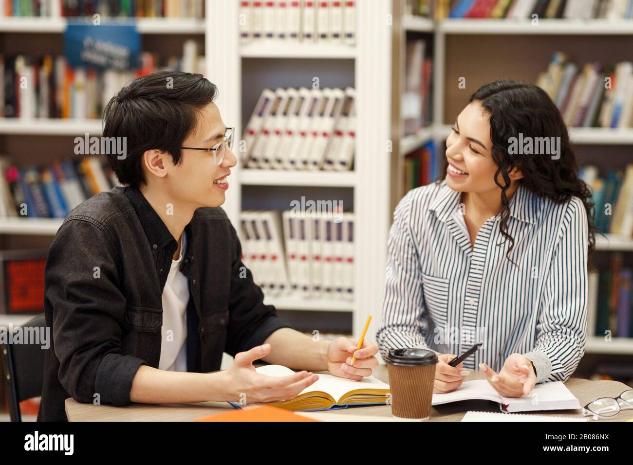 Multicultural couple sharing ideas in modern library Stock Photo - Alamy