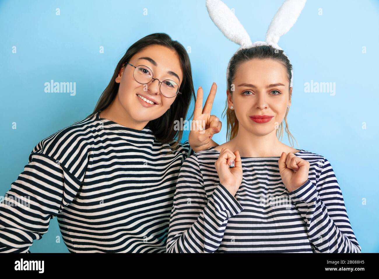 Cute bunnies. Young emotional women isolated on gradient blue studio ...