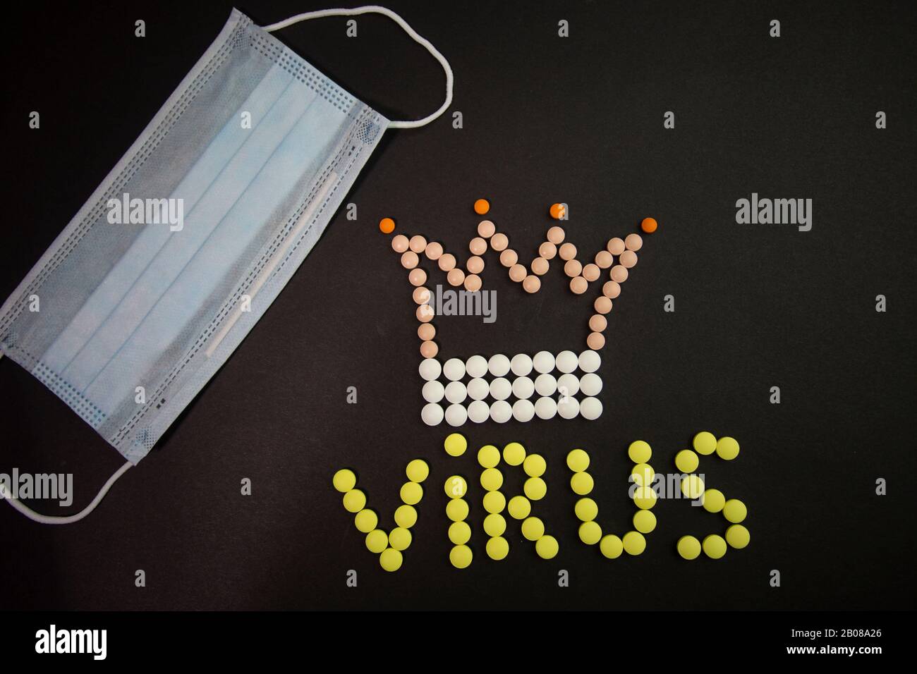 Coronavirus laid out black background from tablets. Medical face mask ...