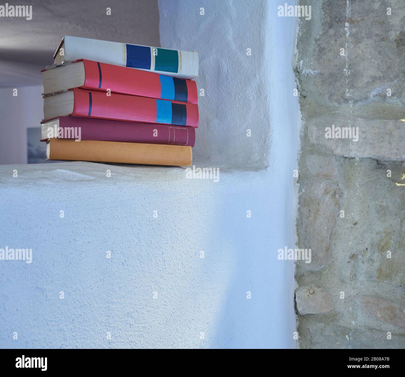 Five stacked books placed inside a high space in wall book titles right ...