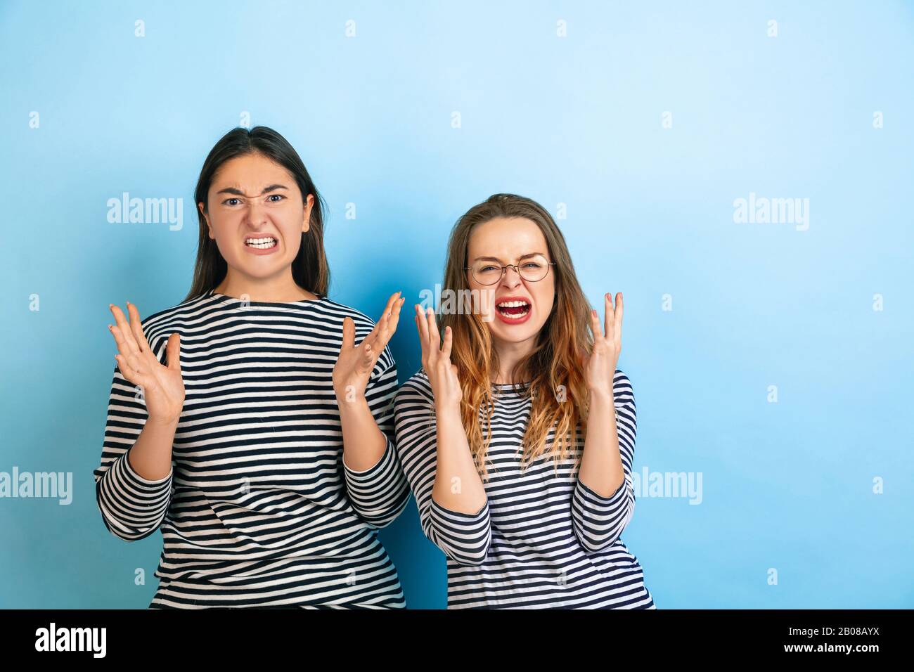 Angry, screaming. Young emotional women isolated on gradient blue ...