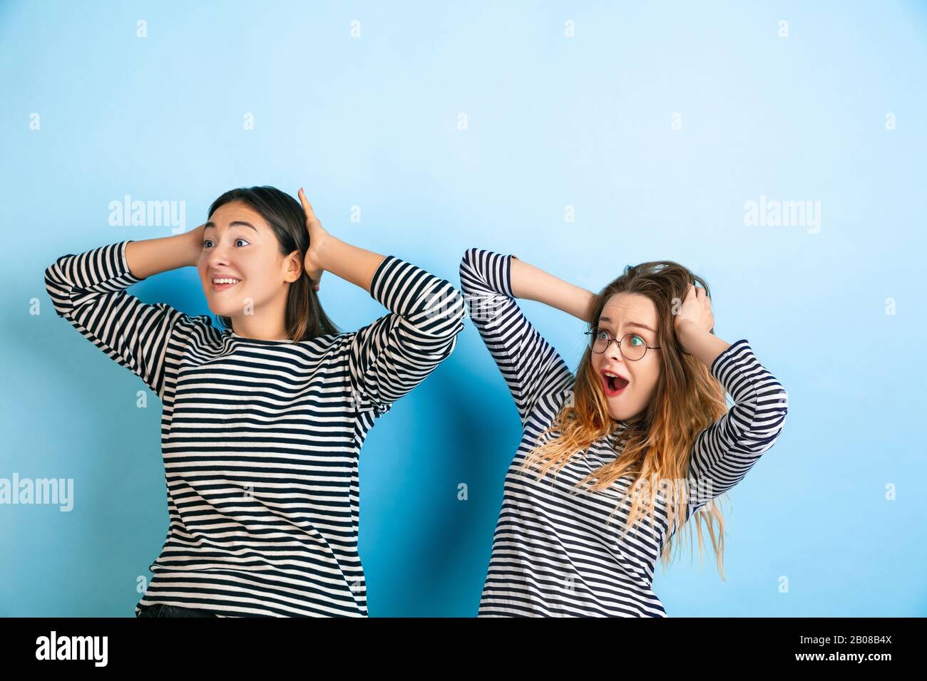 Astonished, shocked. Young emotional women isolated on gradient blue ...