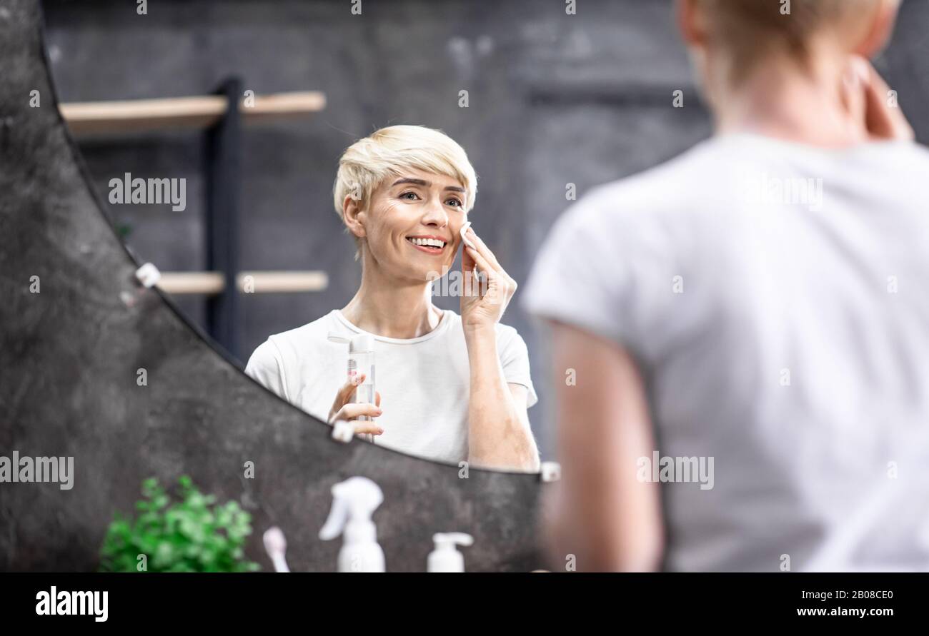 Lady Applying Lotion On Face Cleansing Skin Standing In Bathroom Stock ...