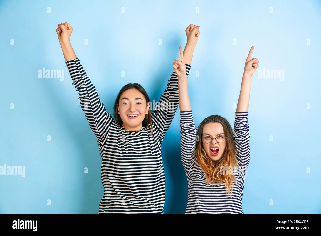 Happy winners, pointing. Young emotional women isolated on gradient ...