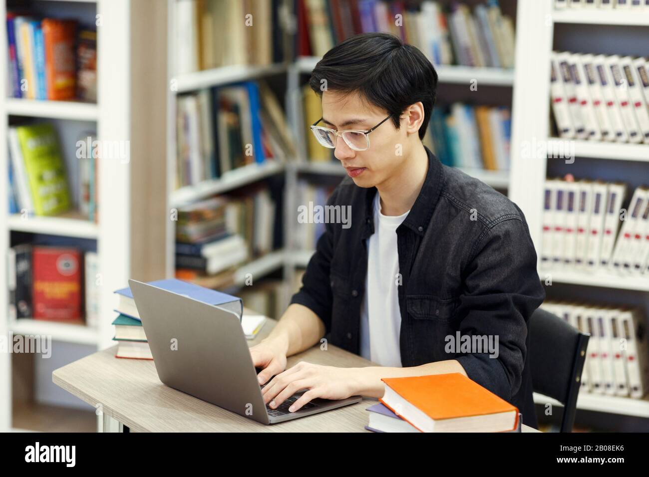 Focused chinese guy working in modern library Stock Photo - Alamy