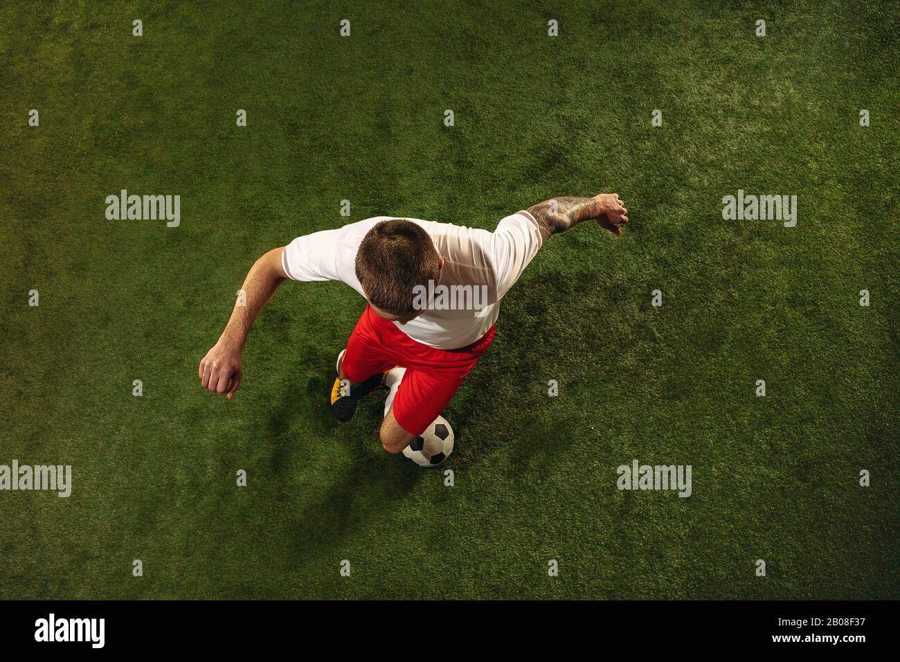 Top view of caucasian football or soccer player on green background of ...