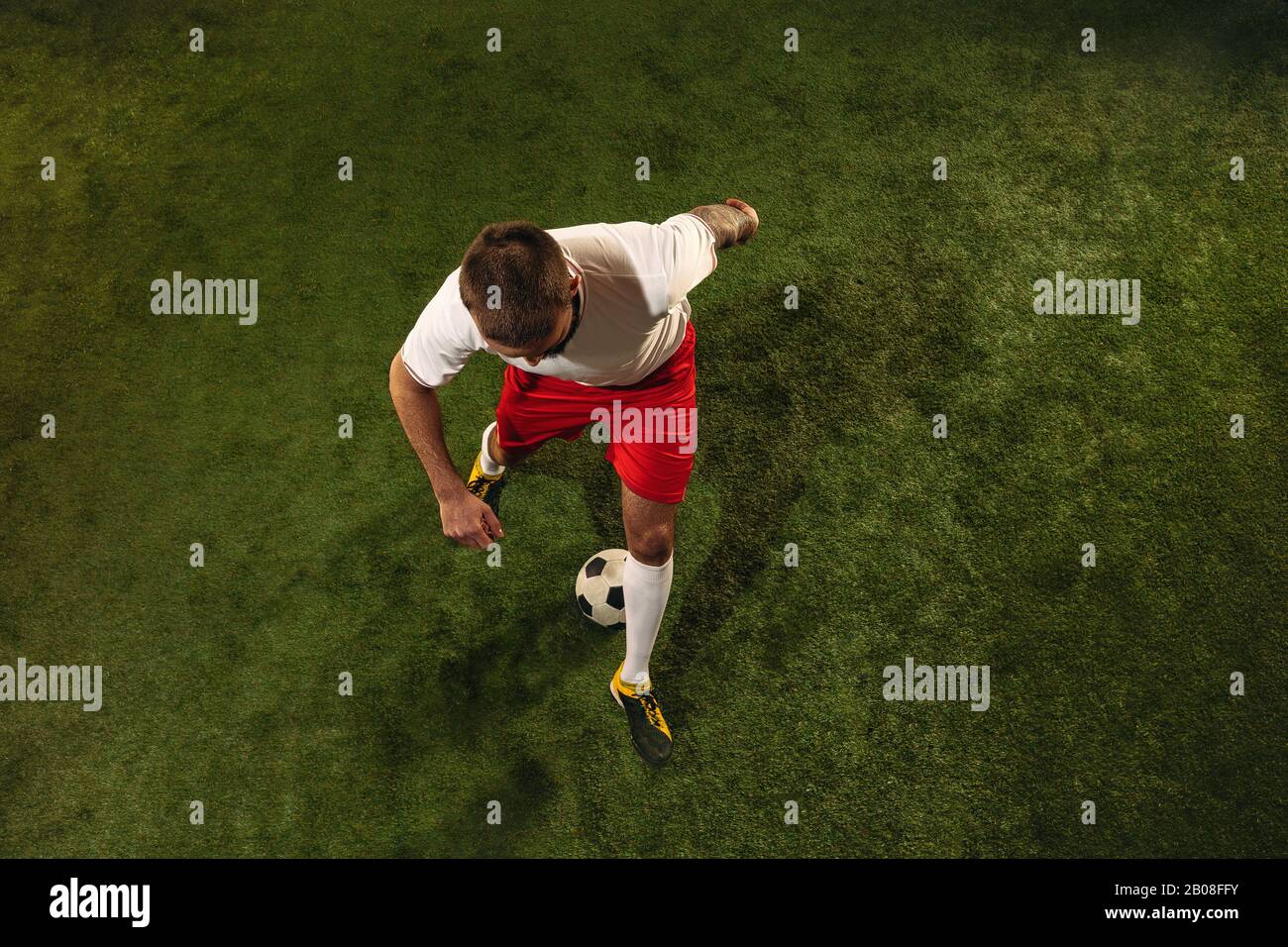 Top view of caucasian football or soccer player on green background of ...
