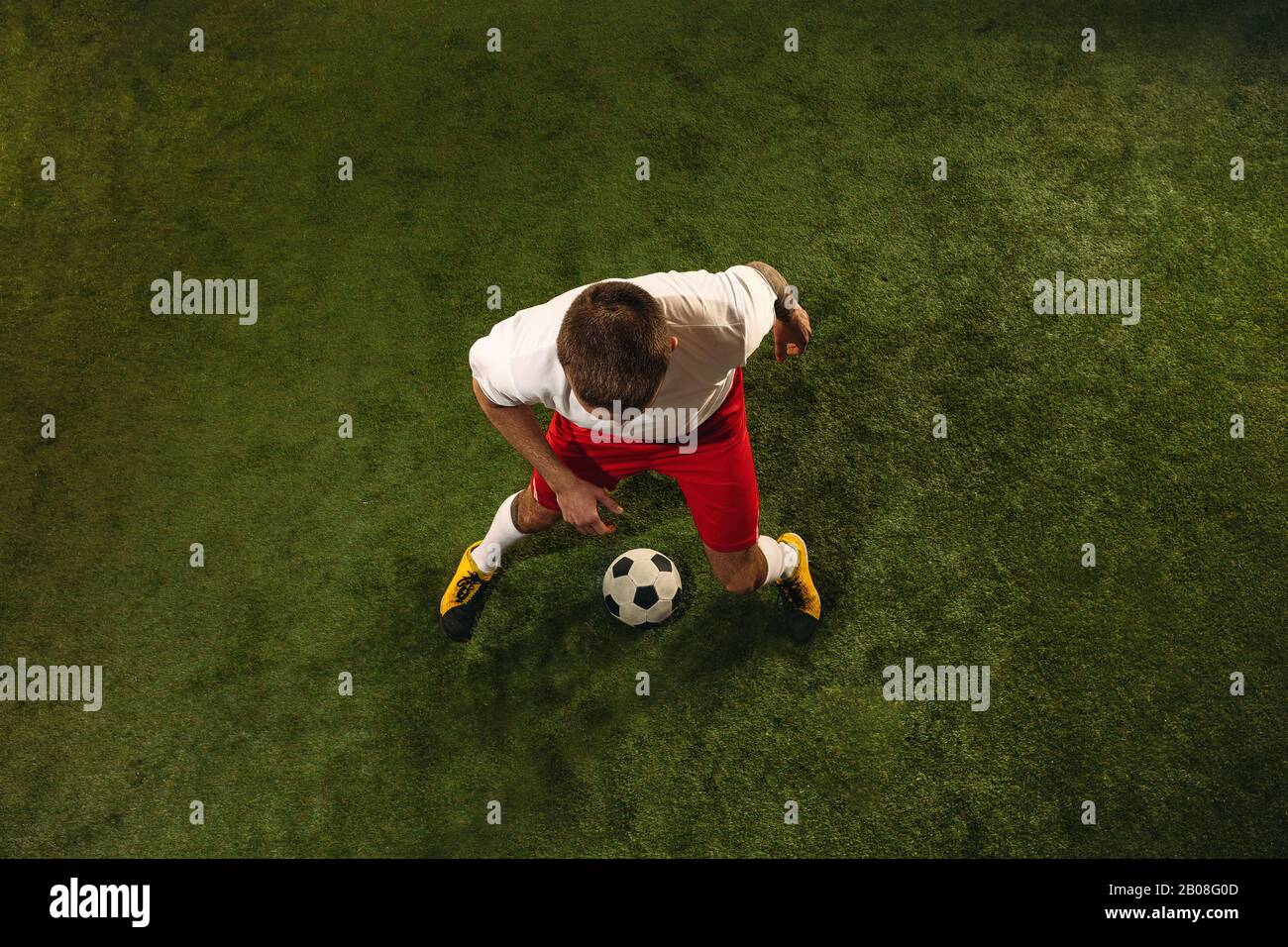Top view of caucasian football or soccer player on green background of ...