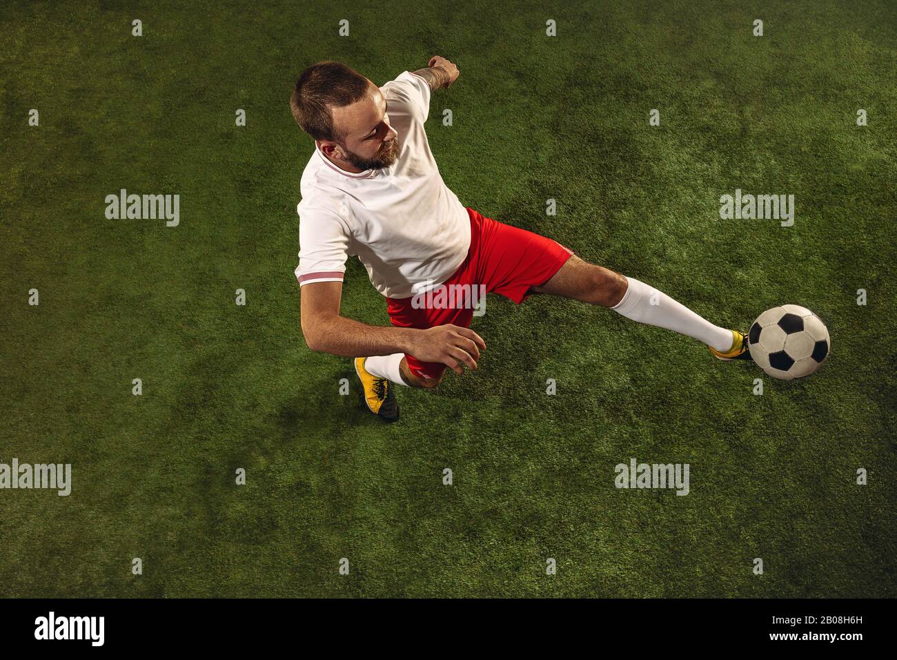 Top view of caucasian football or soccer player on green background of ...