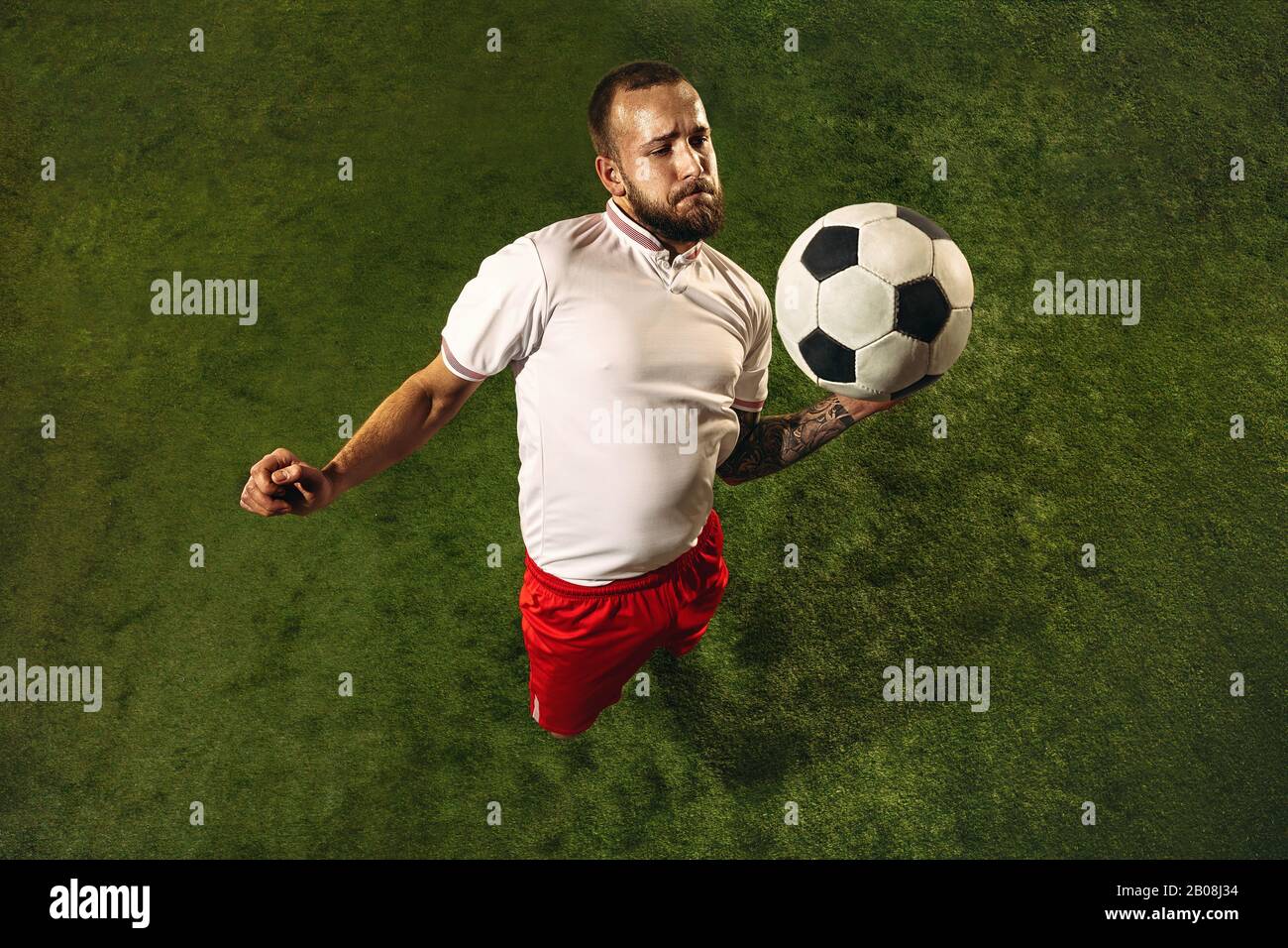 Top view of caucasian football or soccer player on green background of ...