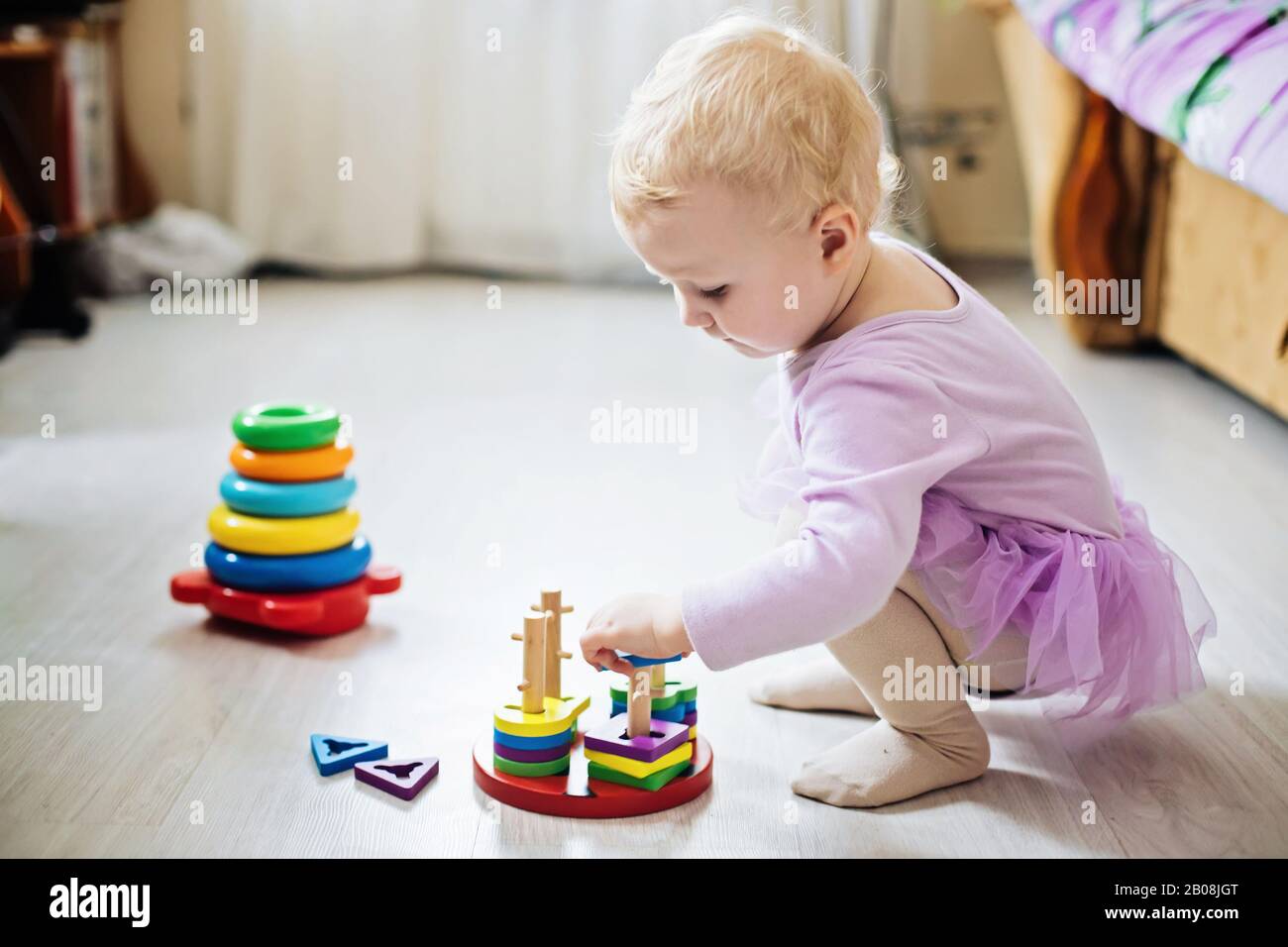 girl plays logical pyramid on floor in living room on sunny day ...