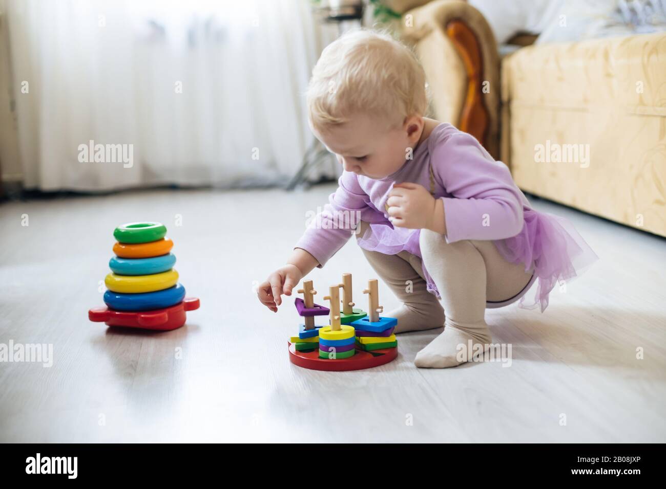 Montessori wooden toy folded pyramid. girl plays logical pyramid on ...