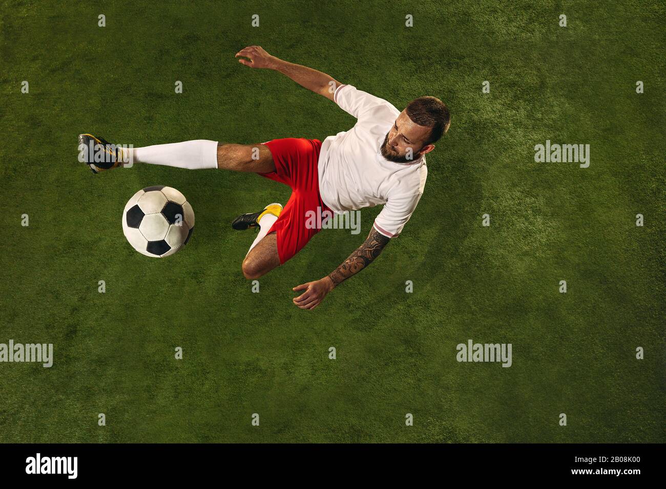 Top view of caucasian football or soccer player on green background of ...