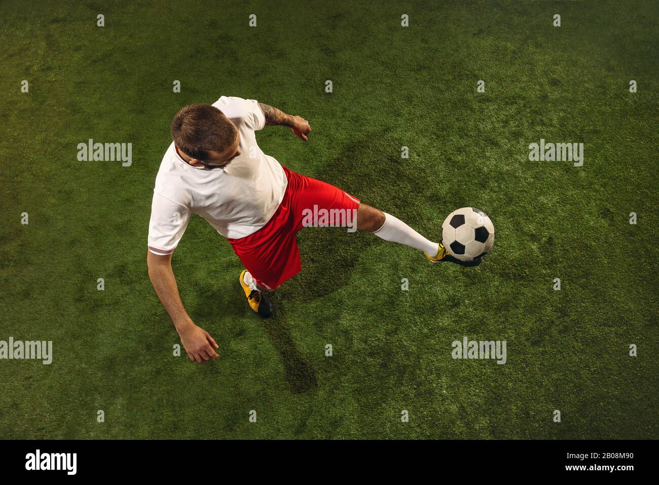 Top view of caucasian football or soccer player on green background of ...