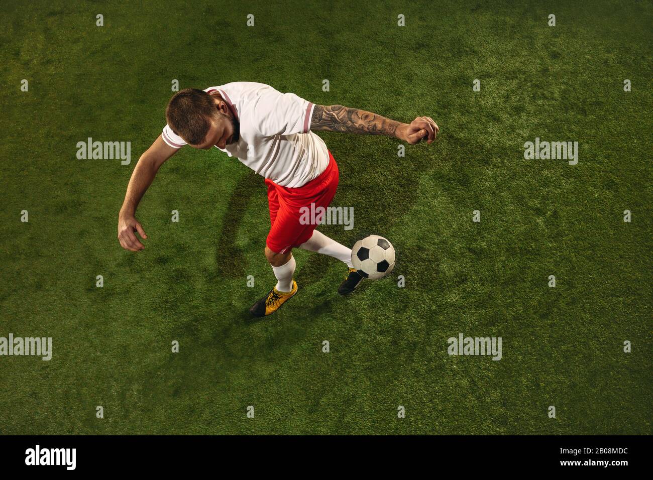 Top view of caucasian football or soccer player on green background of ...