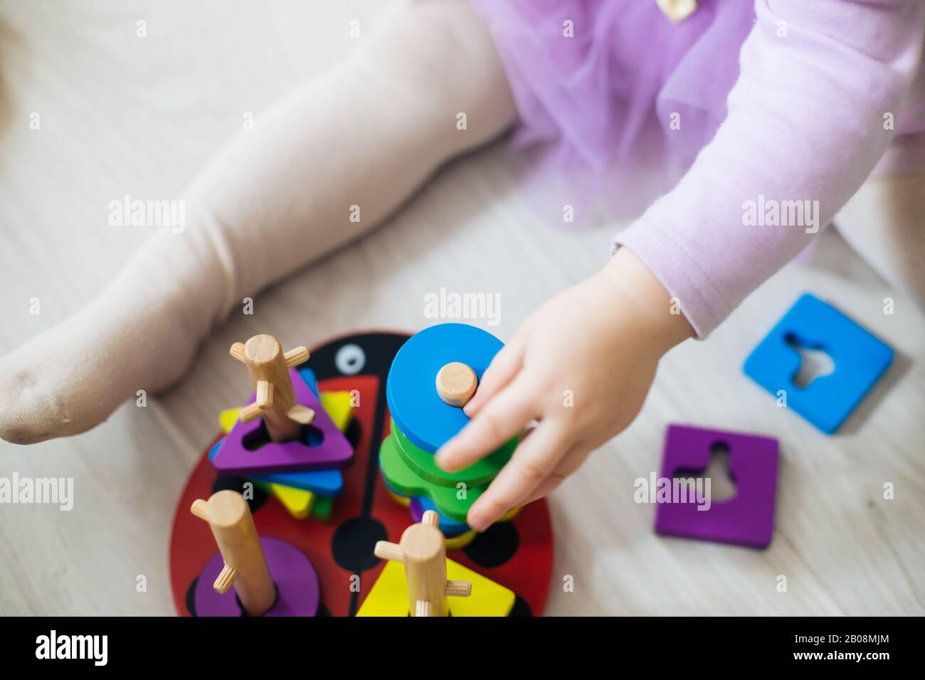 girl plays toys in living room. Montessori wooden toy folded pyramid ...