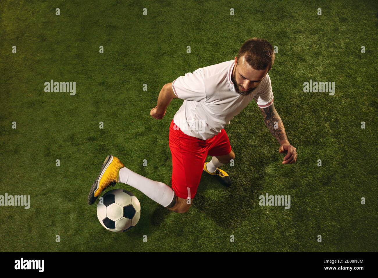 Top view of caucasian football or soccer player on green background of ...