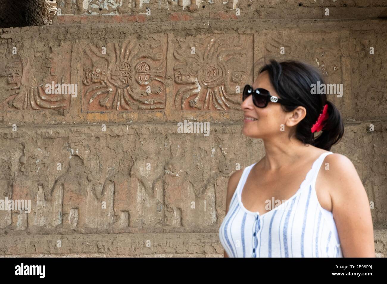 A smiling woman tourist enjoying the carved adobe friezes of the ...