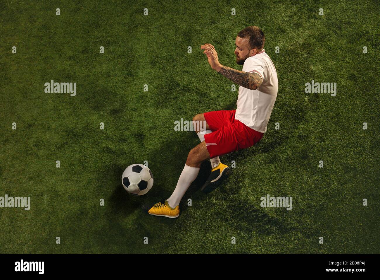 Top view of caucasian football or soccer player on green background of ...
