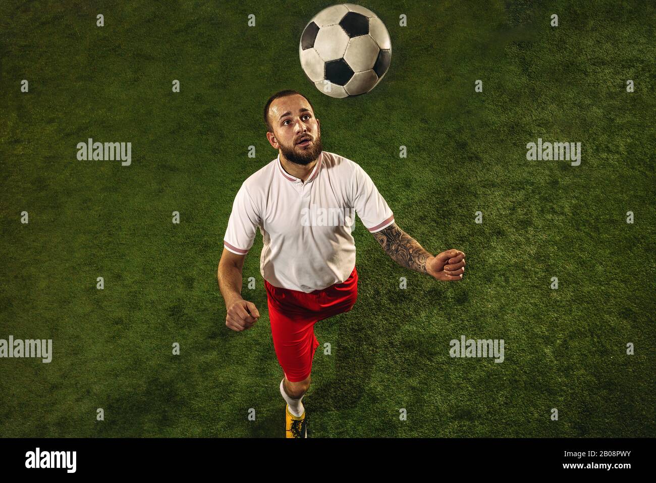 Top view of caucasian football or soccer player on green background of ...
