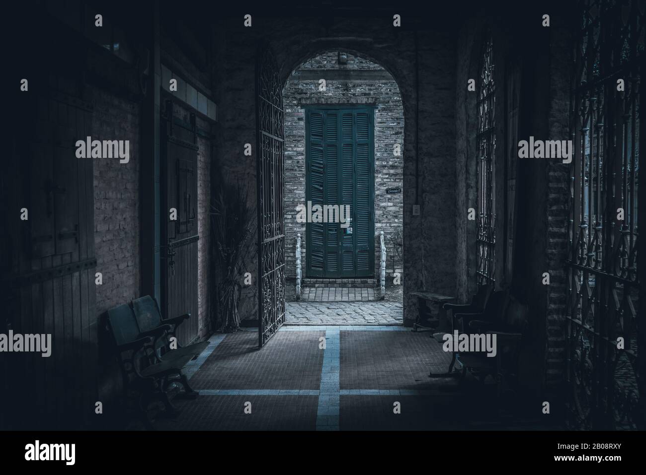 Scary passage leading to an old brick arch with a rusty open iron gate ...