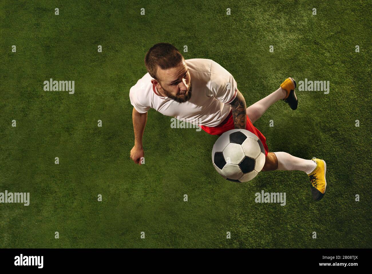 Top view of caucasian football or soccer player on green background of ...