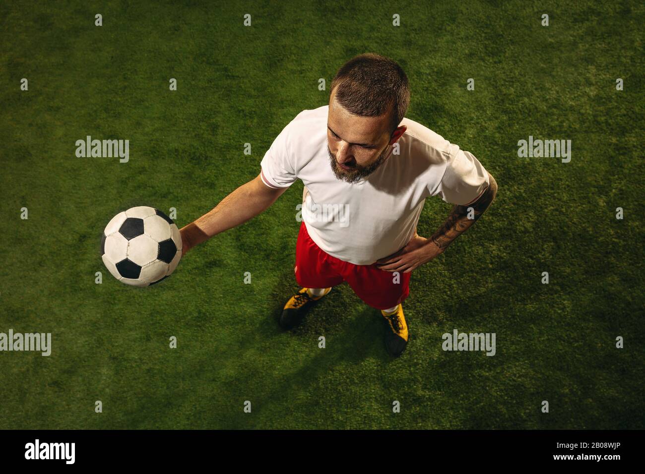 Top view of caucasian football or soccer player on green background of ...