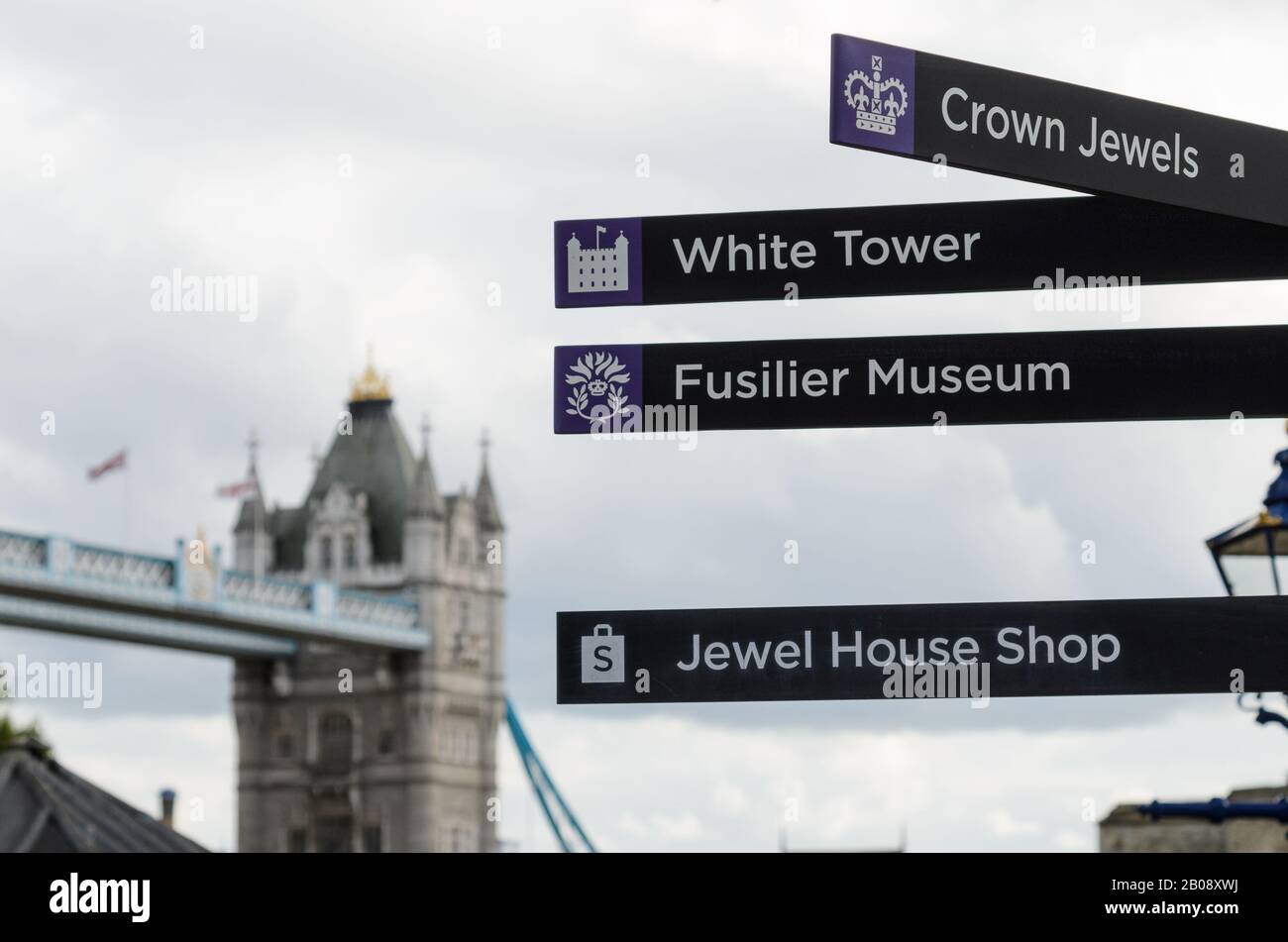 A sign post in the grounds of the Tower of London with Tower Bridge in ...