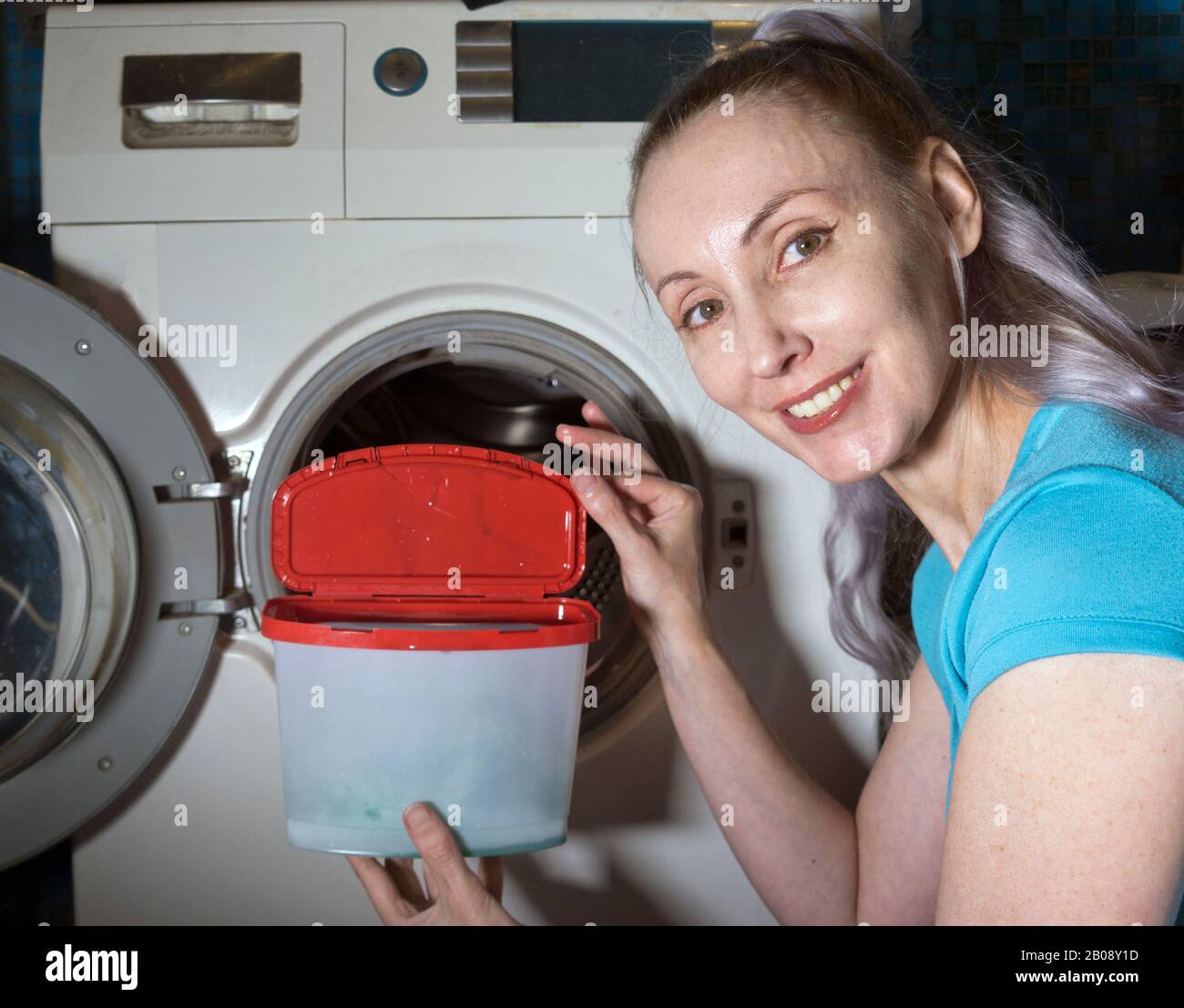 joyful woman in the background of a washing machine holds a box with ...