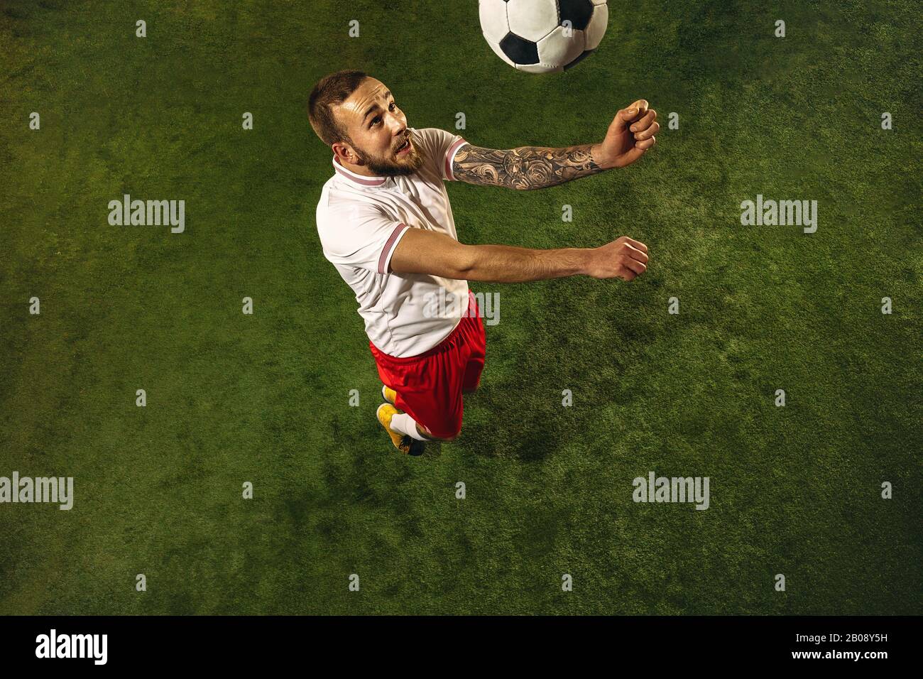 Top view of caucasian football or soccer player on green background of ...