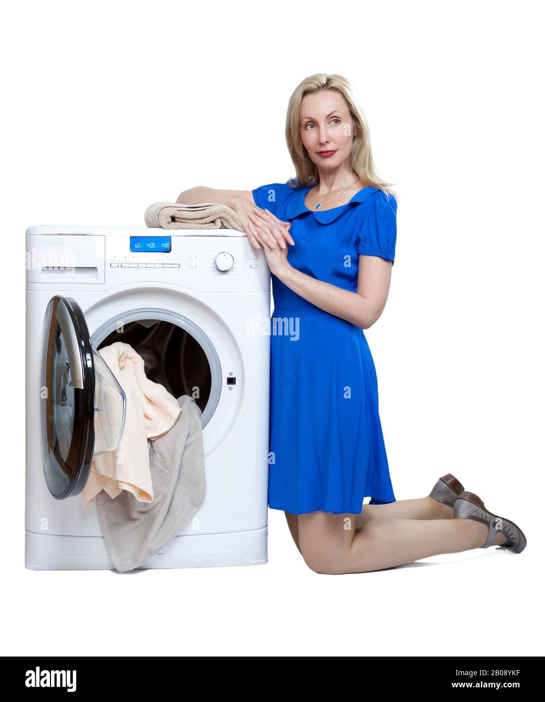 woman in a dress sits next to a new washing machine. Clean towels ...