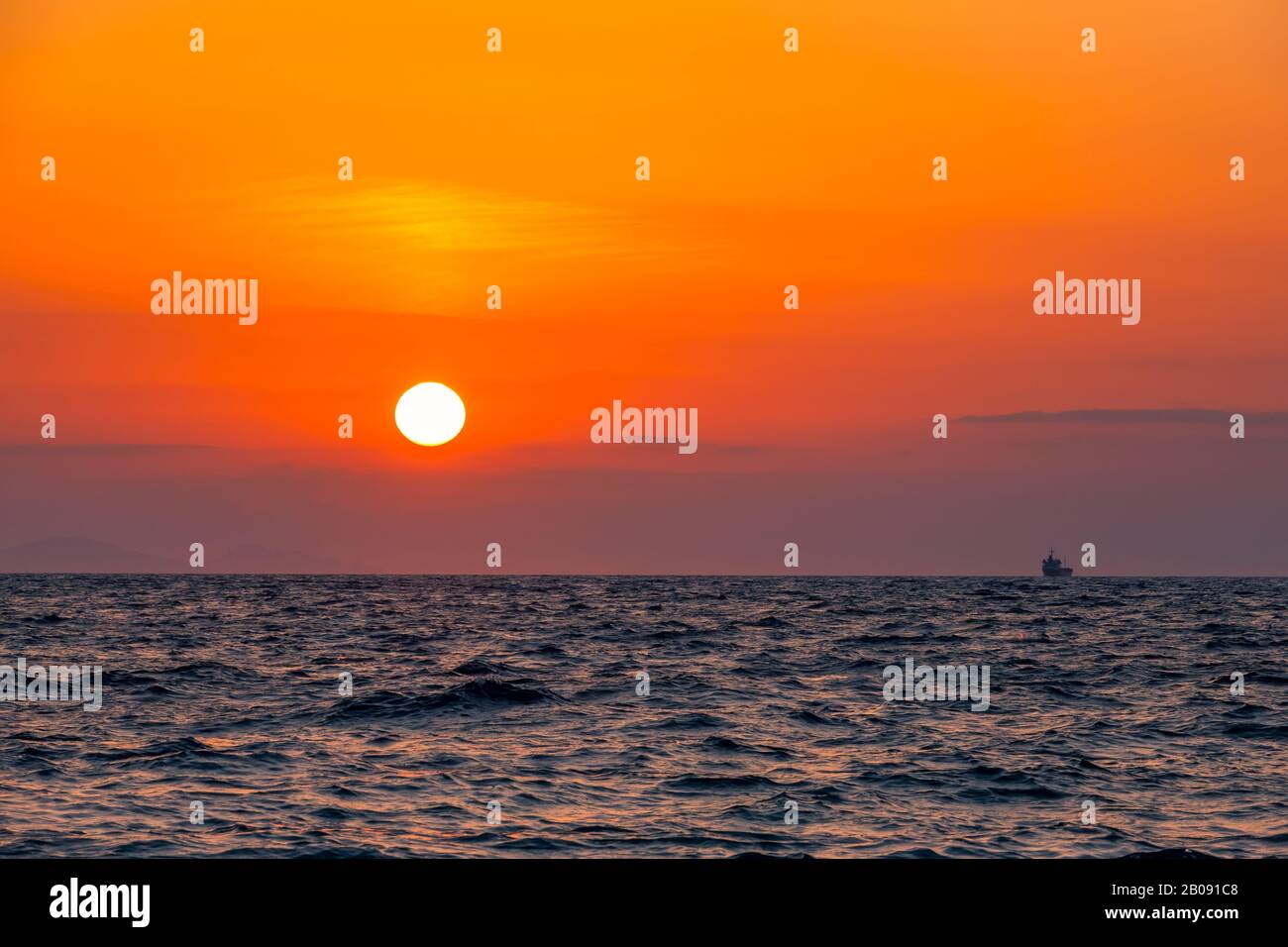Boundless sea. Unbelievable red sunset. Small freighter ship on the ...