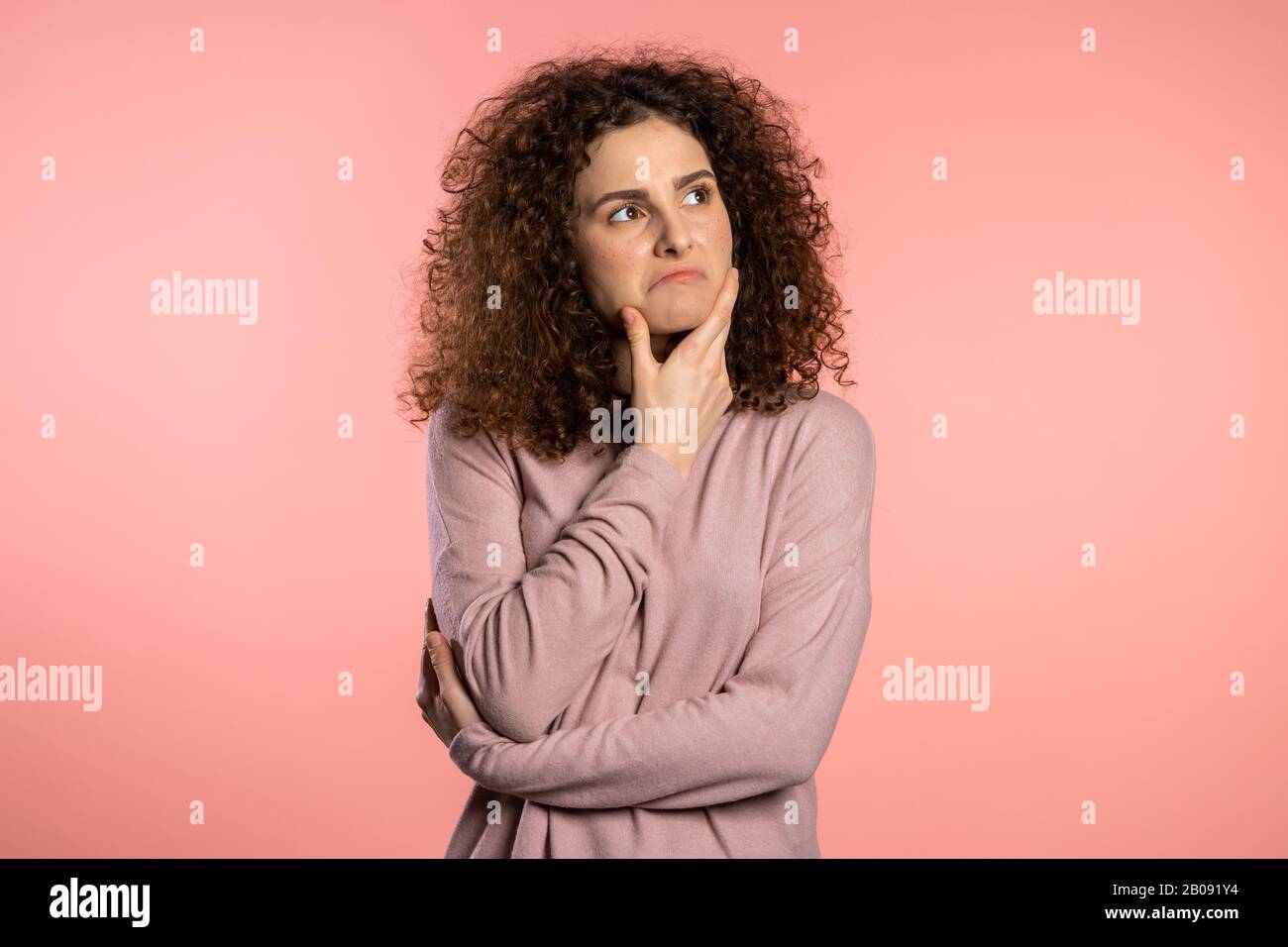 Thinking woman looking up and around on pink background. Worried ...