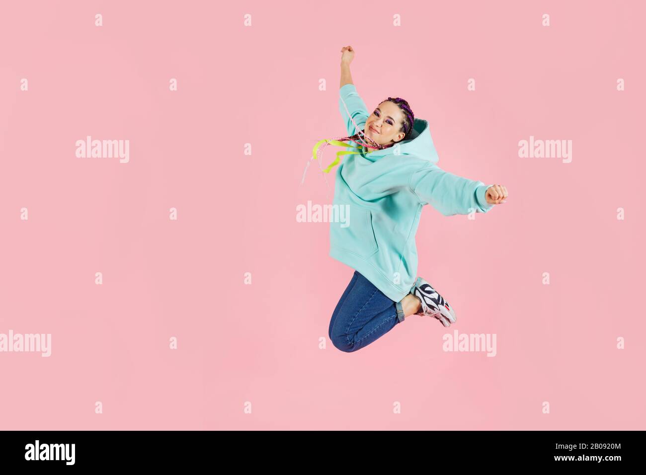 Beautiful young fit dancer in blue hoodie dancing and jumping isolated ...