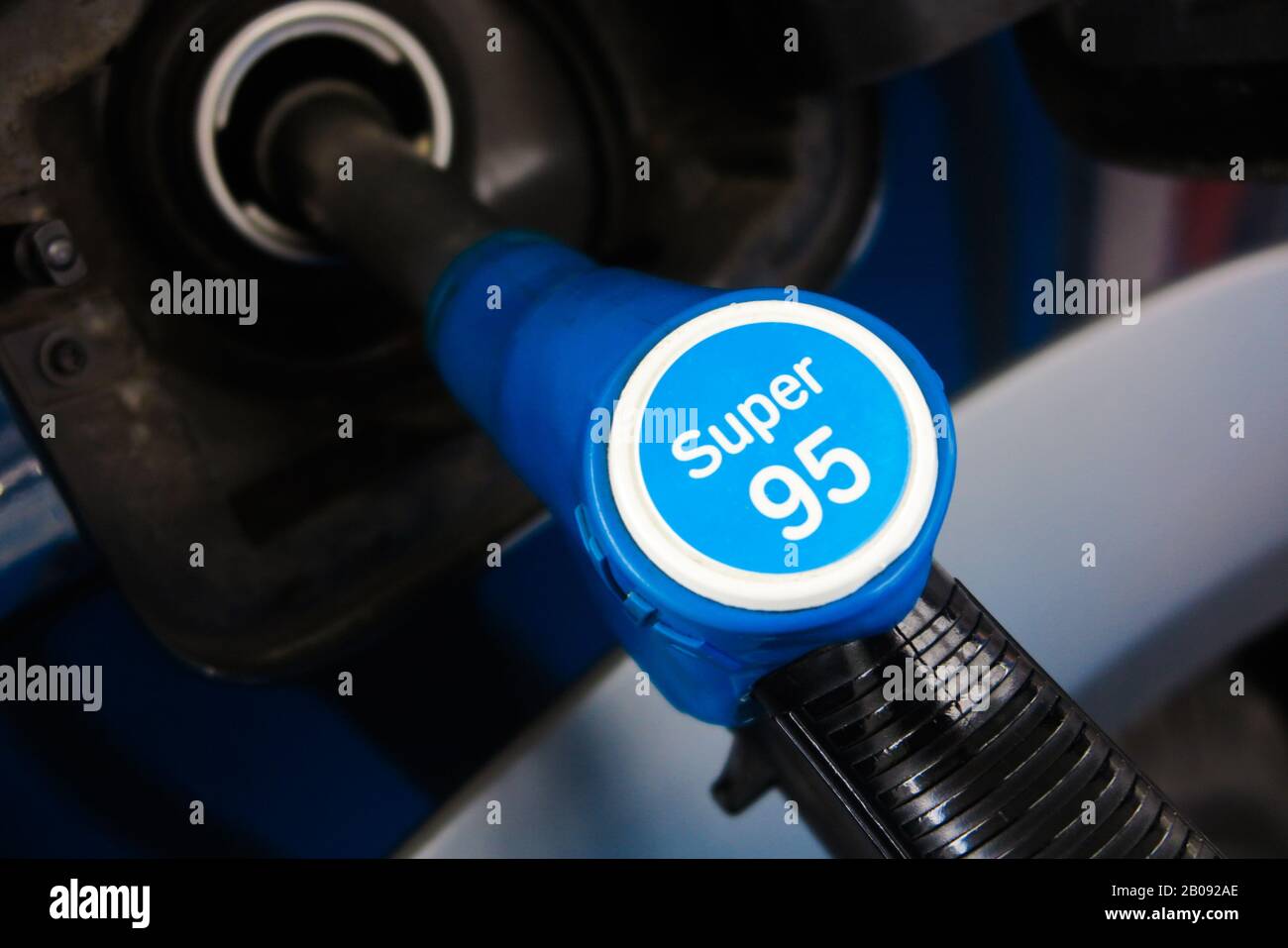 Close up of isolated petrol nozzle in opening of car tank filling with ...
