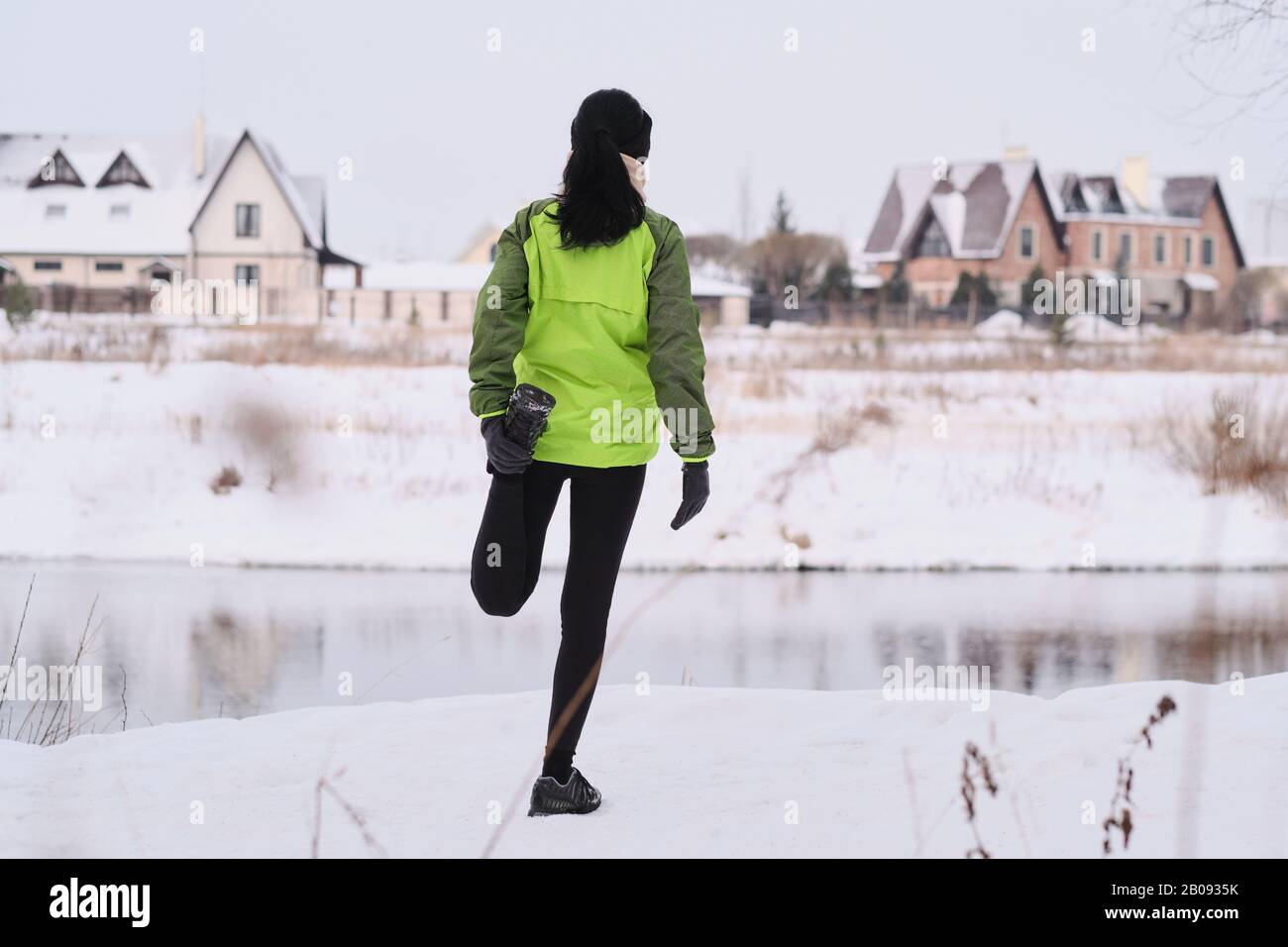 Rear view of brunette woman doing quad stretch exercise while ...