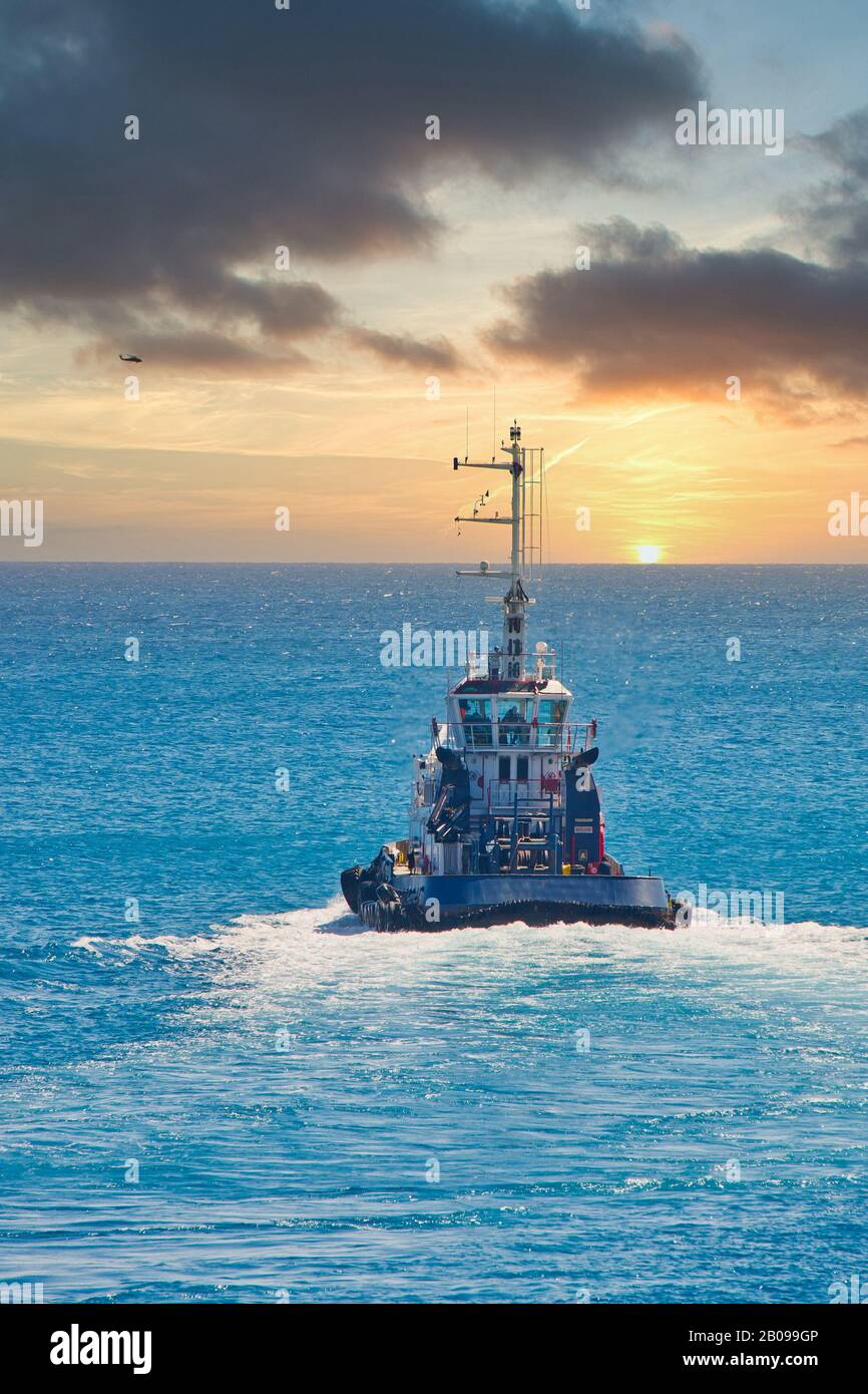 Tugboat Heading into Sunset Stock Photo - Alamy