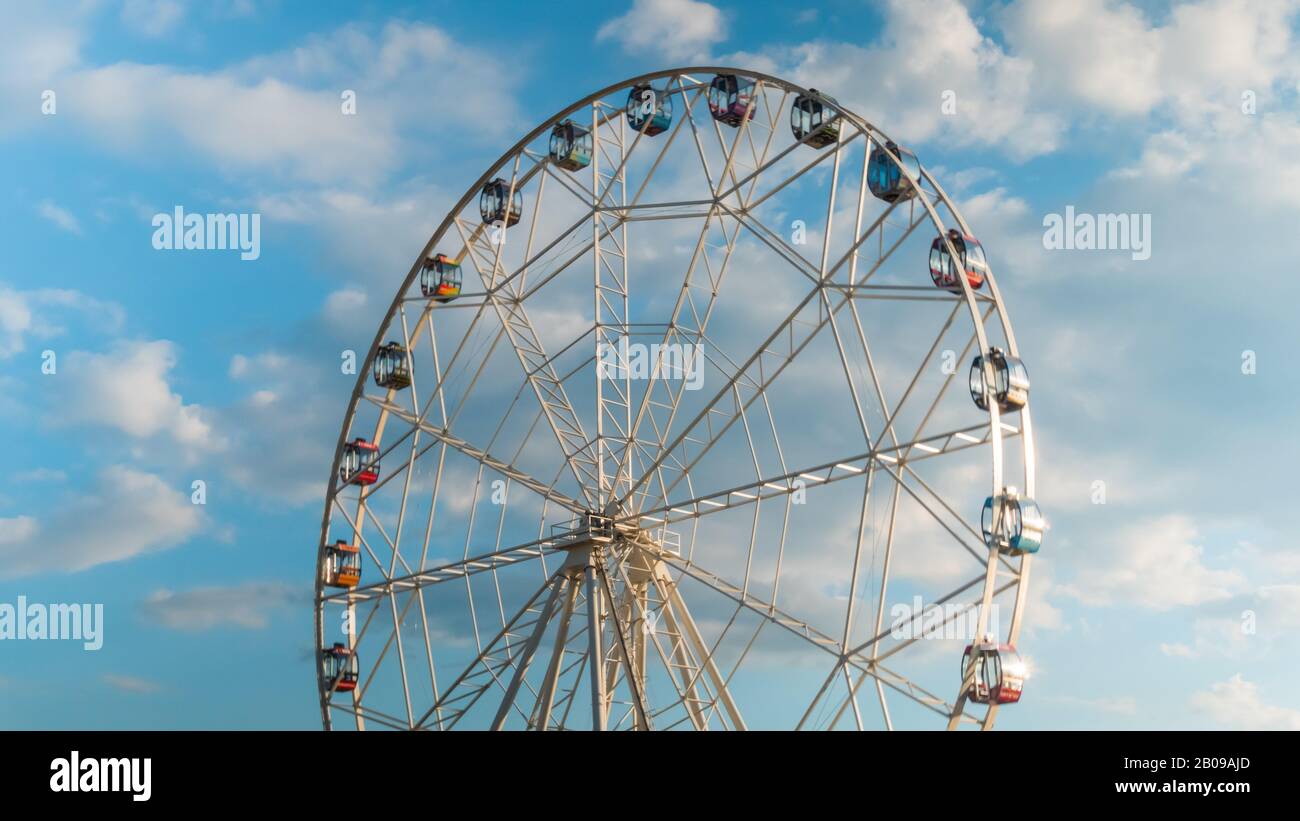 Rotating ferris wheel and white clouds, sunset cloudy sky Stock Photo ...