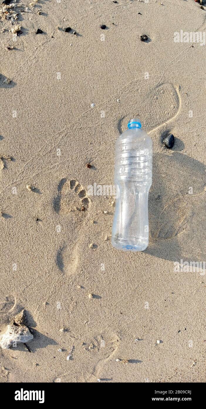 Plastic bottle in the sand, next to the footprints Stock Photo - Alamy