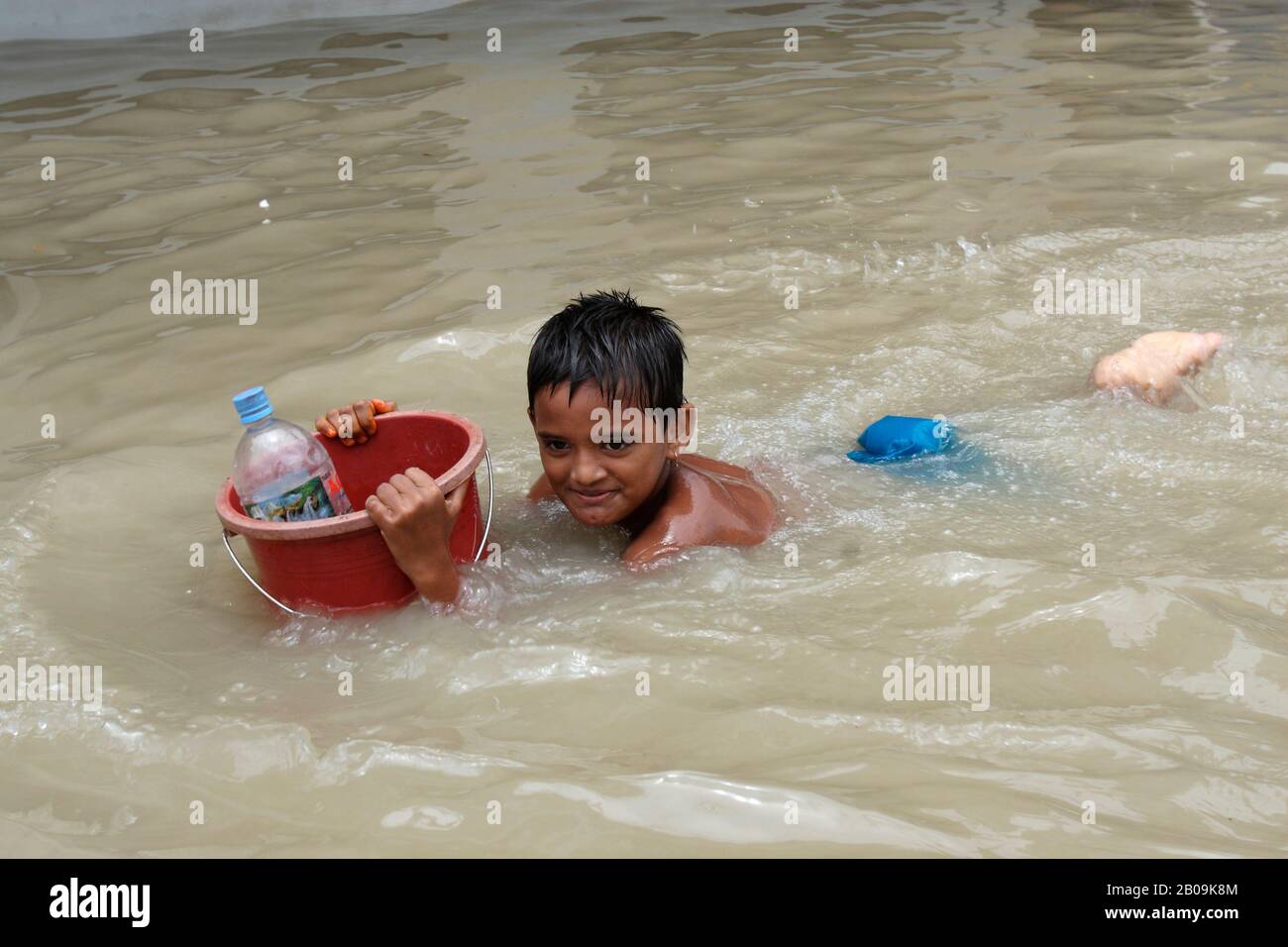 A young girl with drinking water swims across a flooded road in the ...