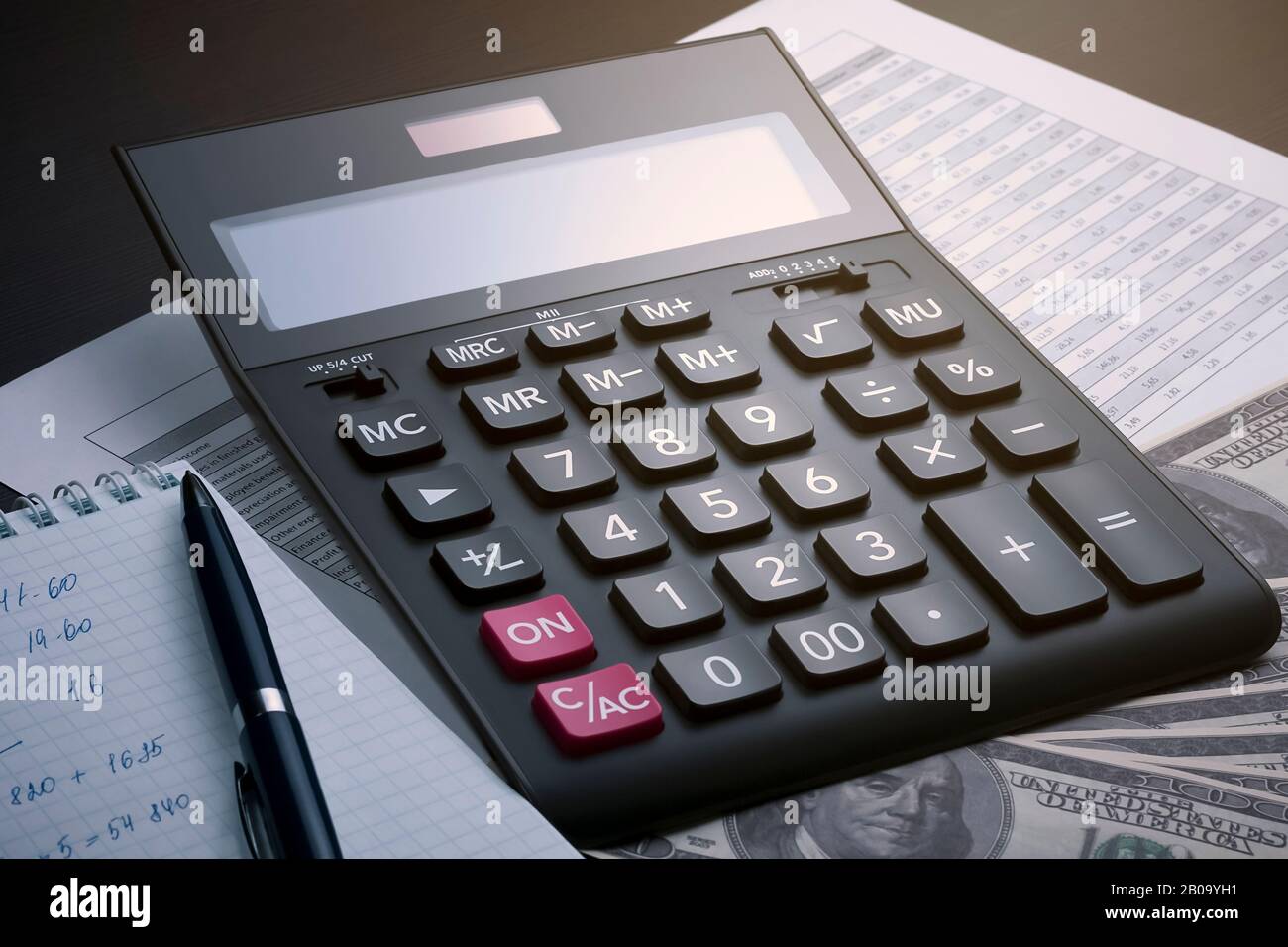 Side view of a black accounting calculator, a report with a table, an ...