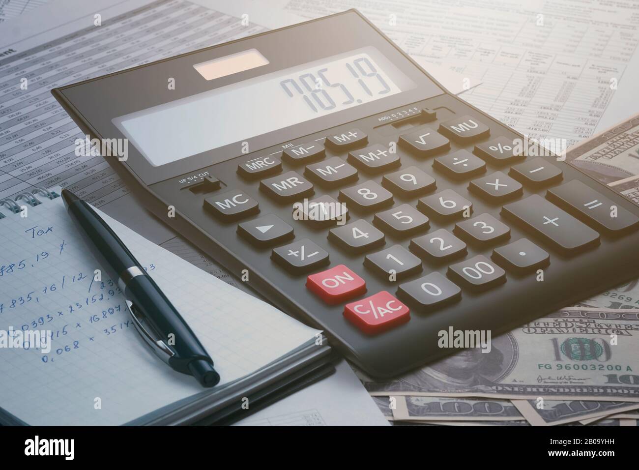 Side view of black accounting calculator, open notebook with notes, pen ...